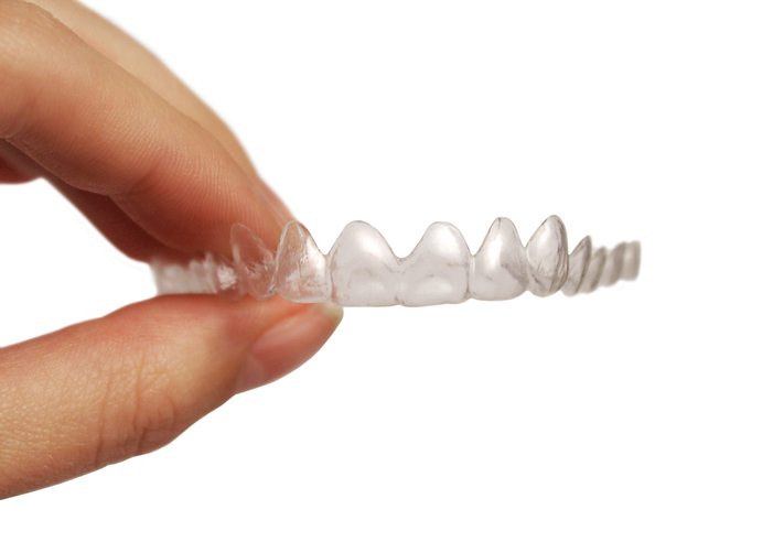 Hand holding invisible retainer - Applegate Dental Blog